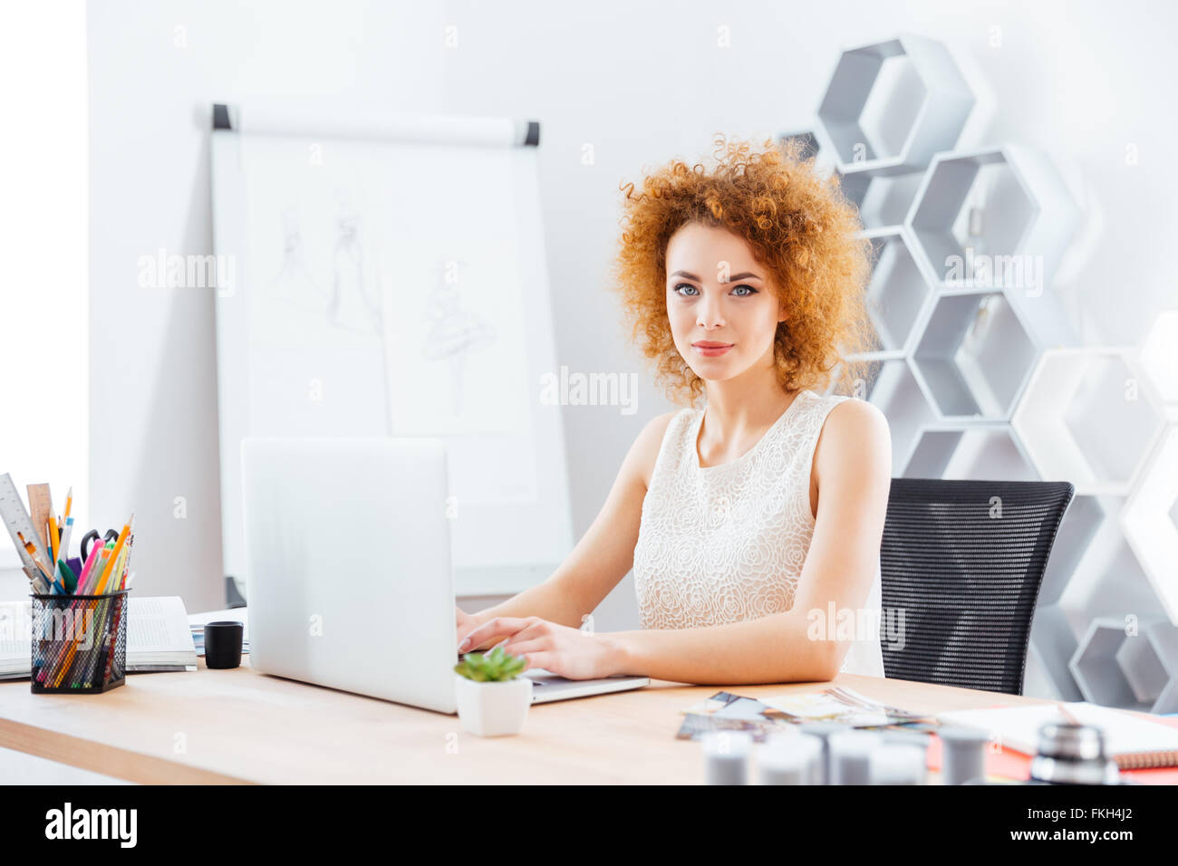 Portrait of beautiful confident young woman fashion designer sitting ...