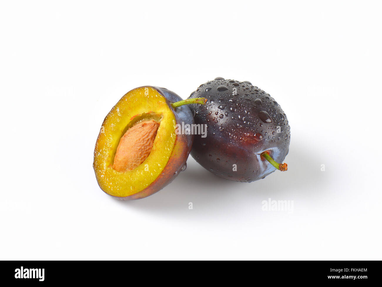 one and half washed plums on white background Stock Photo - Alamy