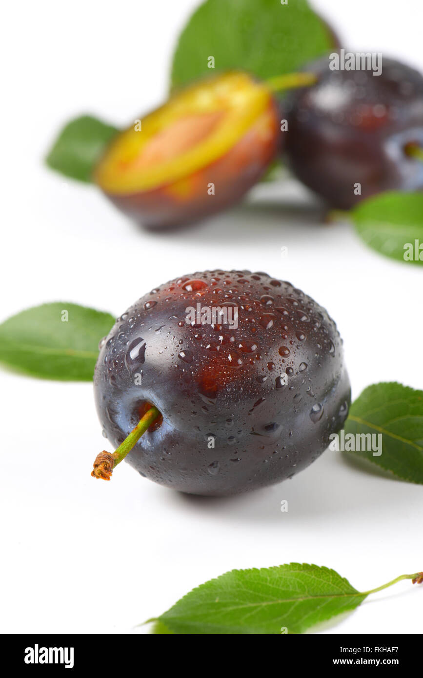 close up of two and half washed plums on white background Stock Photo ...