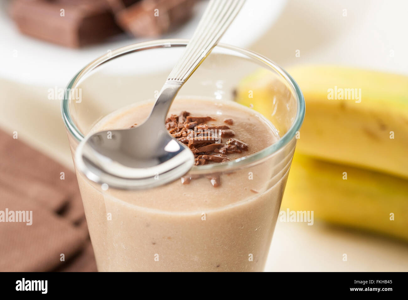 A delicious sweet banana and chocolate smoothie in a glass with a spoon ...