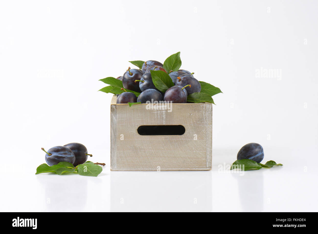 box of ripe plums on white background Stock Photo - Alamy