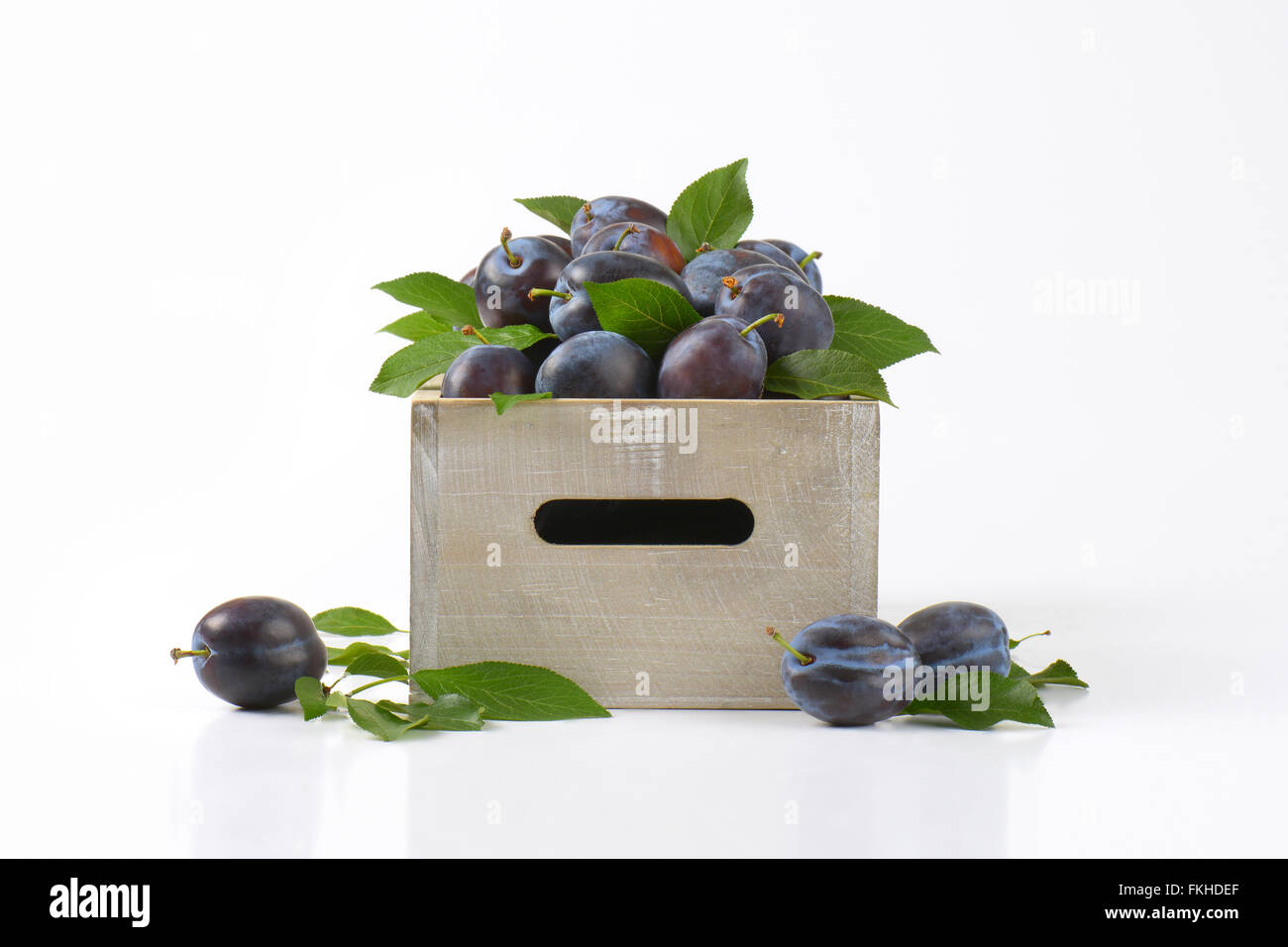 box of ripe plums on white background Stock Photo - Alamy