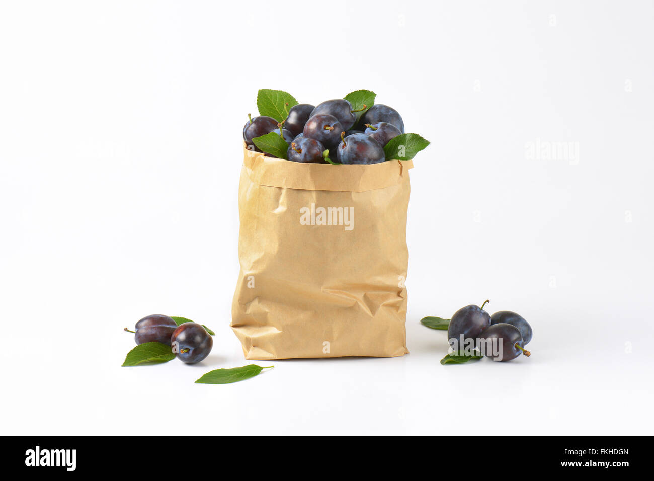 paper bag of ripe plums standing on white background Stock Photo - Alamy
