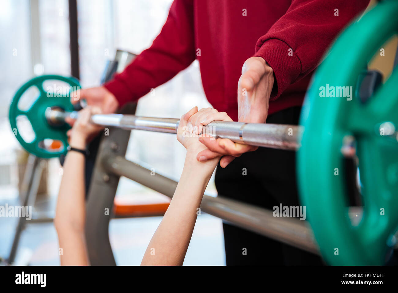 Hands of fitness instructor supporting to young woman athlete working ...