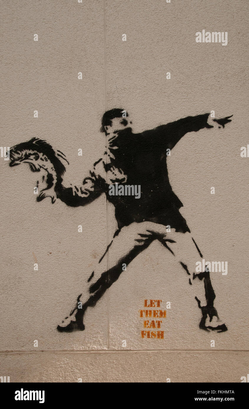 A graffiti mural of a figure throwing a fish, Brixham Harbour, Devon ...