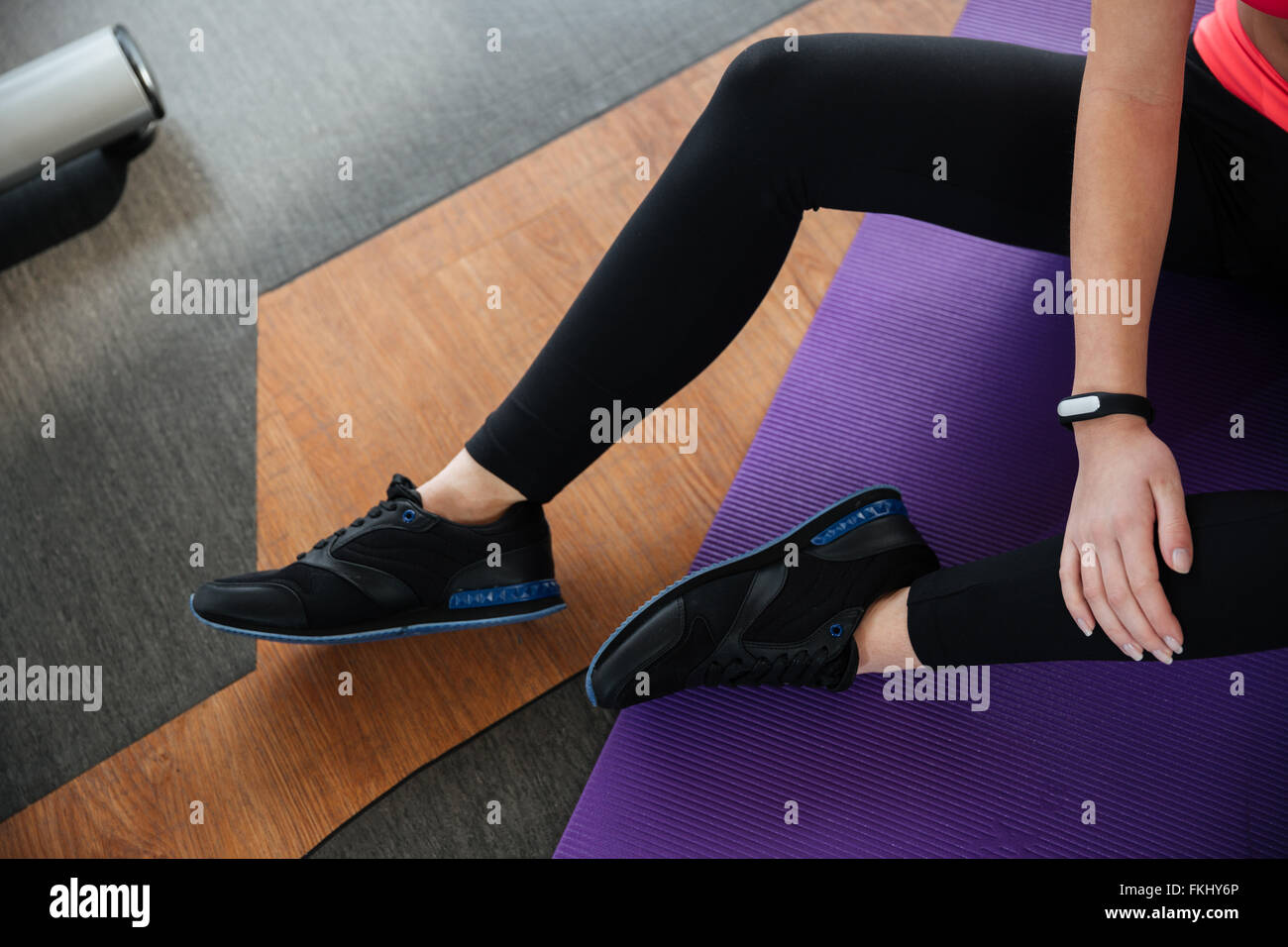 Top view of legs of young sportswoman with fitness tracker on hand in ...
