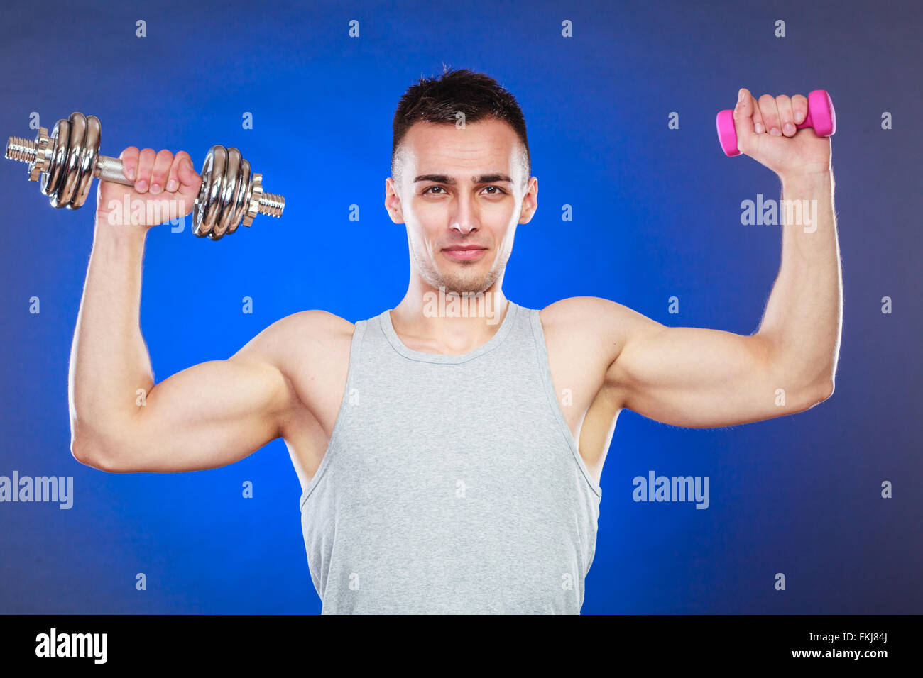 Sporty fit man lifting light and heavy dumbbells weights. Young ...