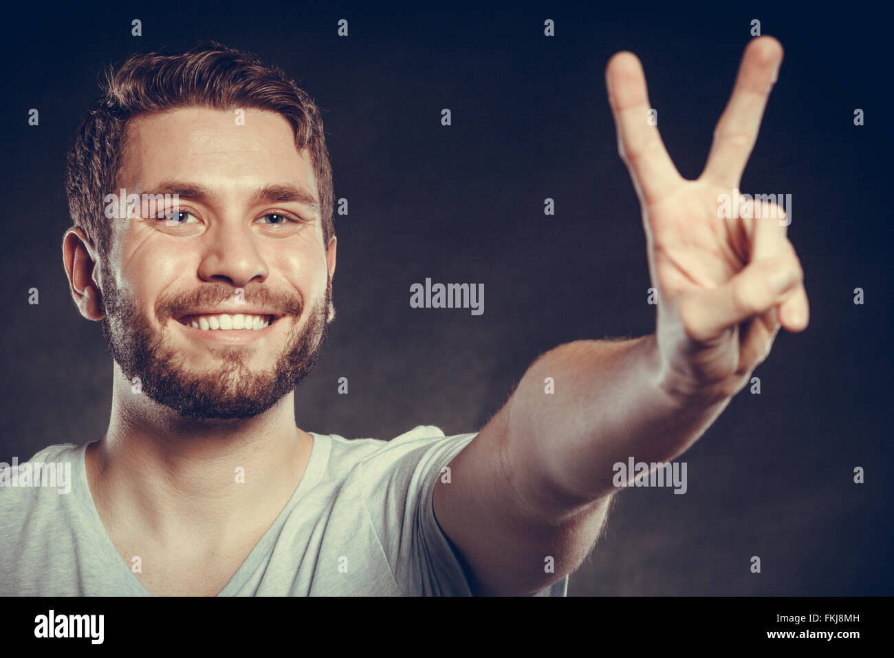Portrait of happy smiling handsome man guy giving peace victory v sign ...