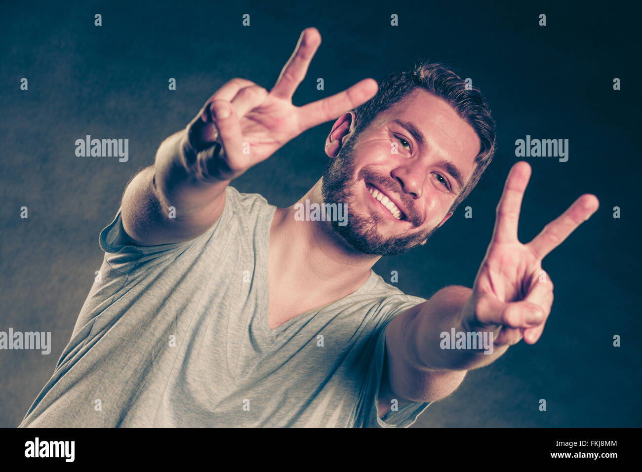 Portrait of happy smiling handsome man guy giving peace victory v sign ...