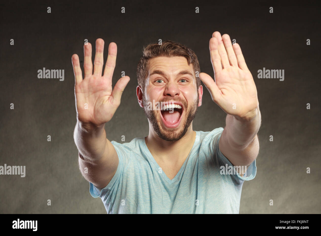 Portrait of handsome man guy giving stop sign gesture and screaming in ...