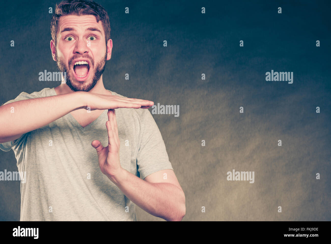 Young handsome man showing time out gesture sign and screaming in ...