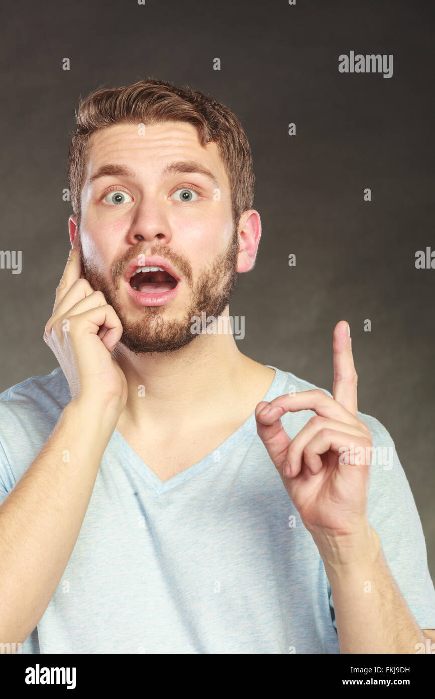 Portrait of surprised scared handsome man pointing at empty blank copy space. Young guy in ...