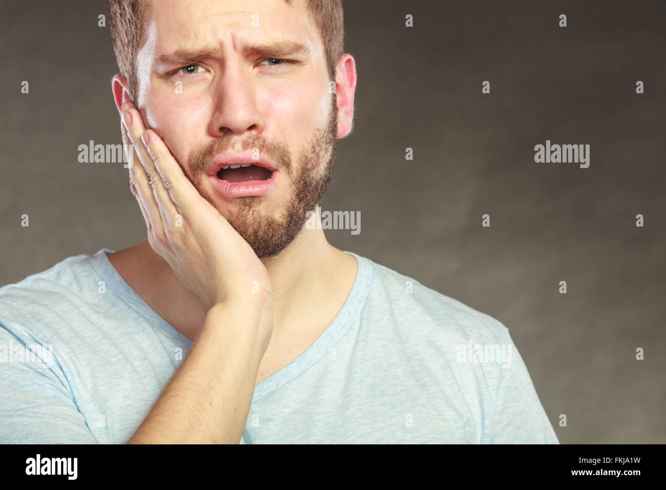 Man suffering from toothache tooth pain. Young guy in studio on black ...