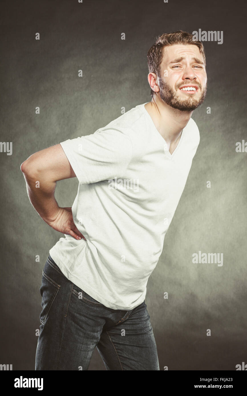 Man suffering from backache back pain. Young guy in studio on black ...