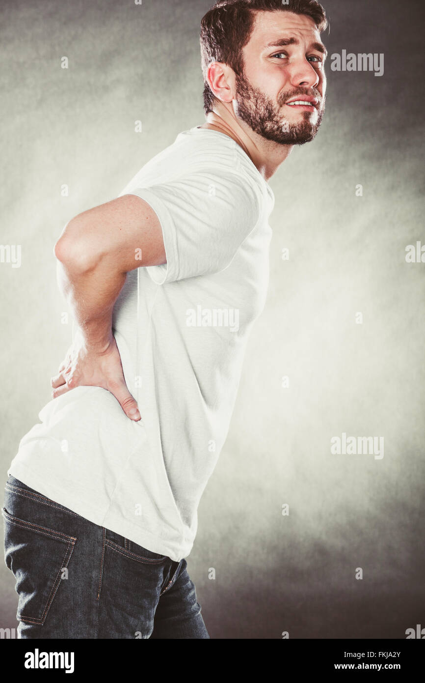 Man suffering from backache back pain. Young guy in studio on black ...
