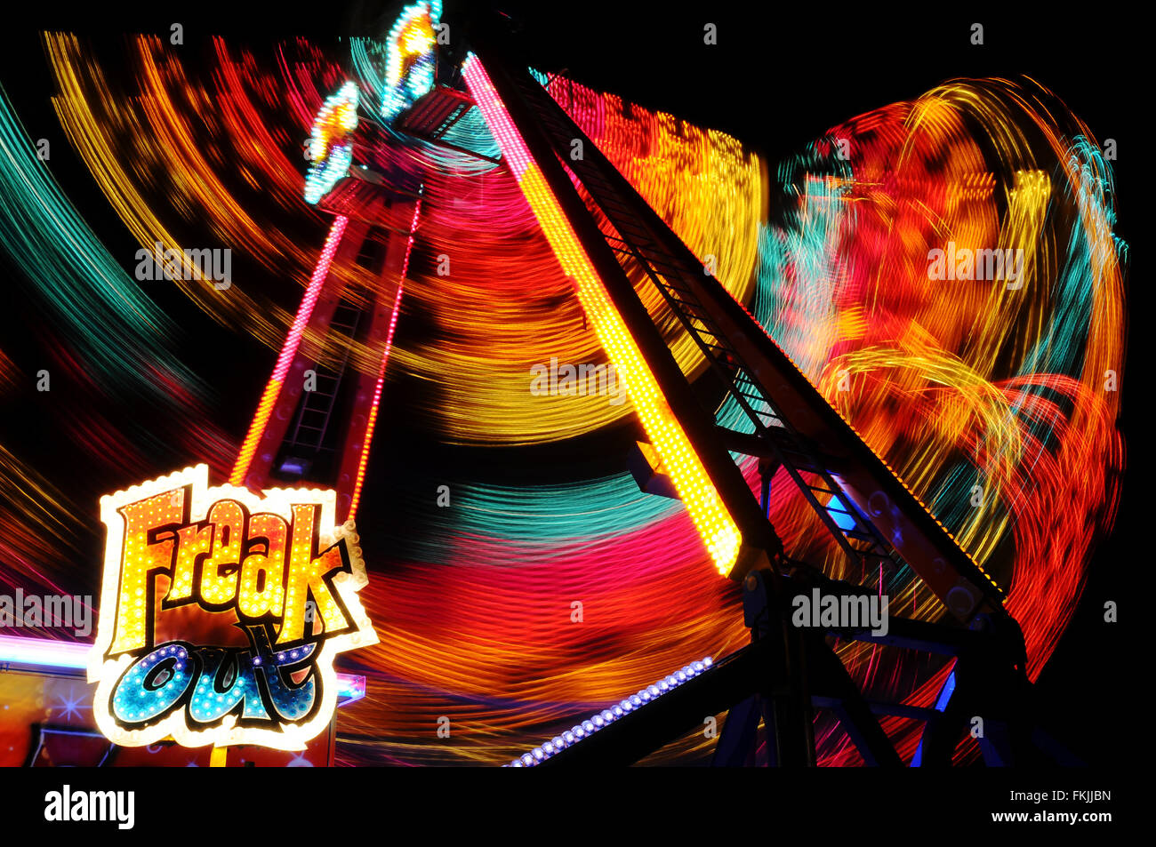 Long exposure shot, taken at night, of a colorfully lit fair ride ...