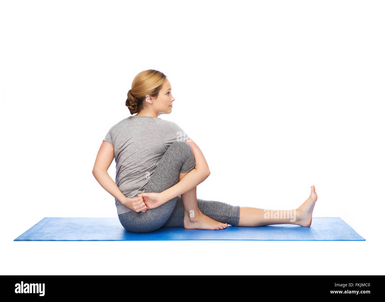 woman making yoga in twist pose on mat Stock Photo - Alamy