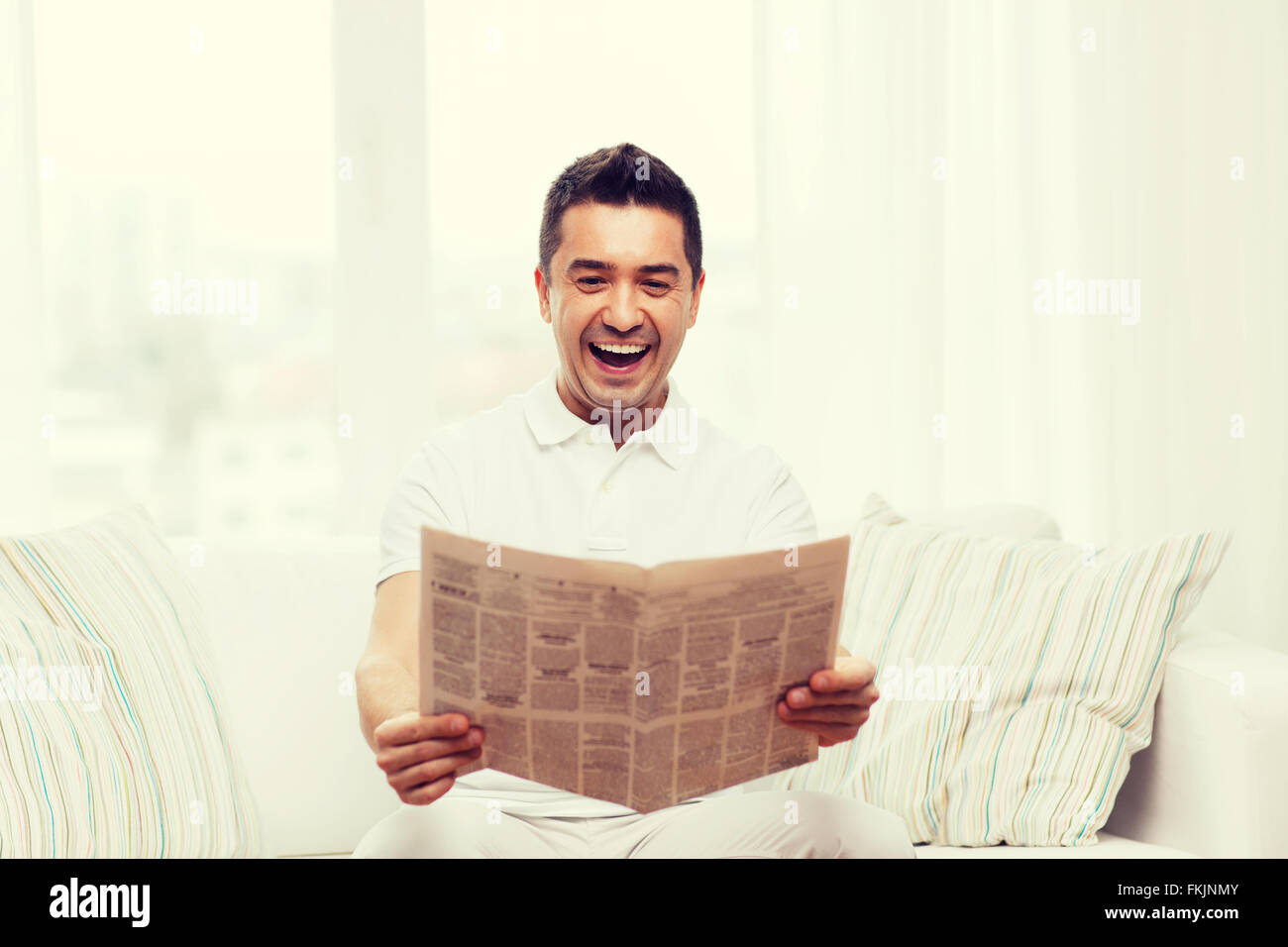 happy man reading newspaper and laughing at home Stock Photo - Alamy