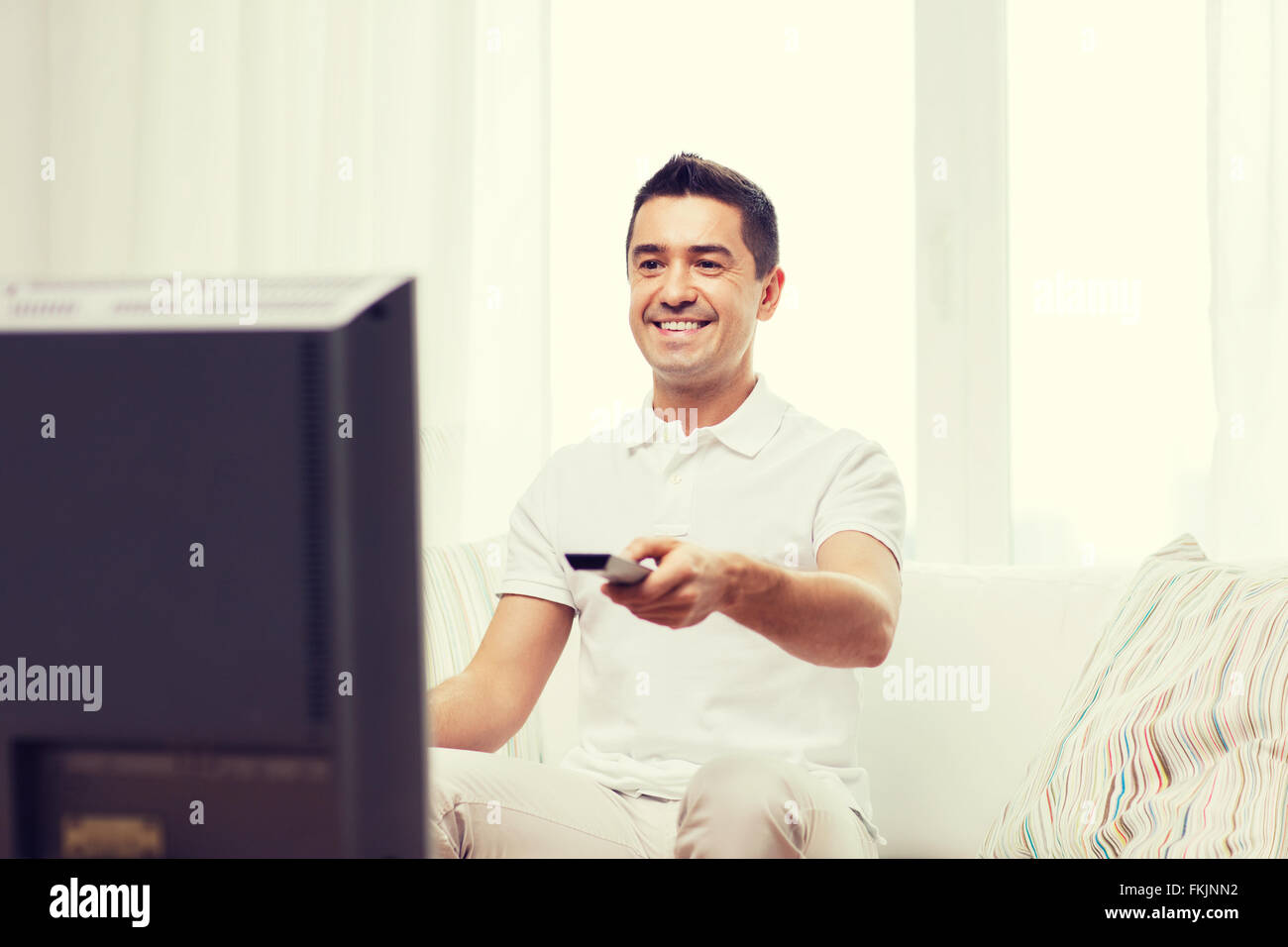 smiling man with remote control watching tv Stock Photo - Alamy
