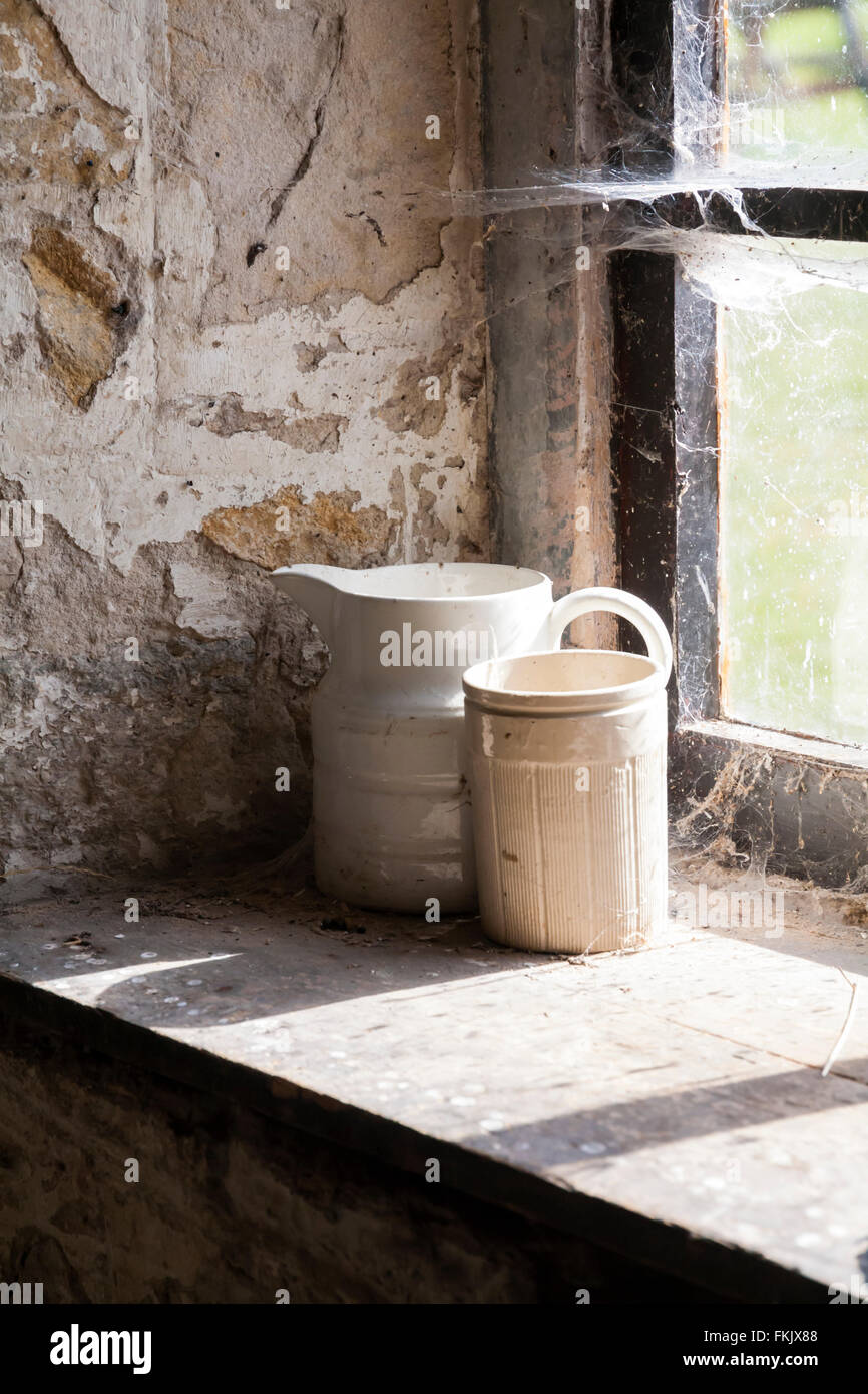 Old jug and container in window covered in cobwebs in old barn ...
