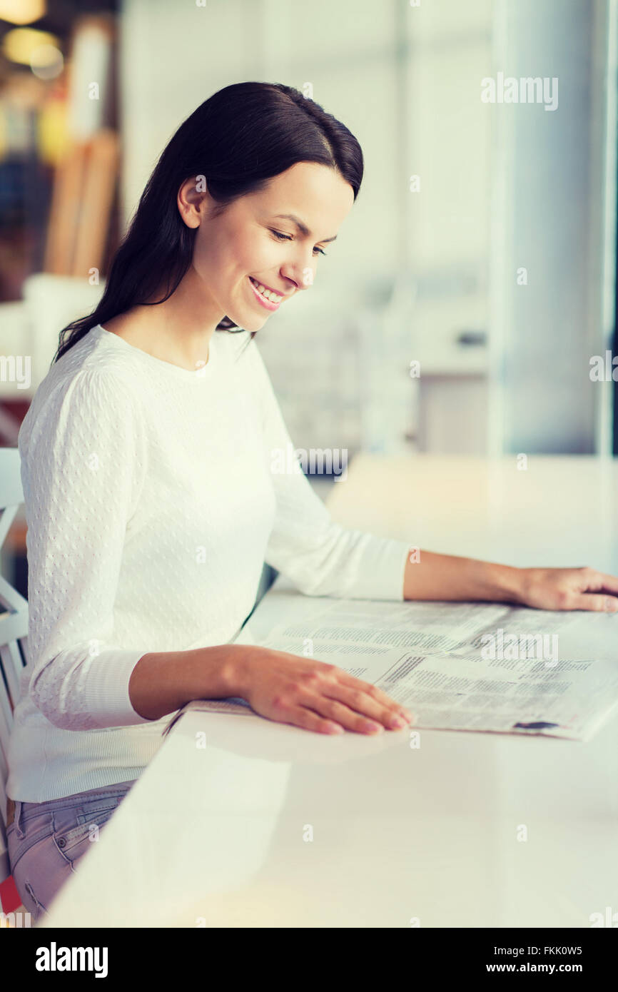 smiling young woman reading newspaper at cafe Stock Photo - Alamy