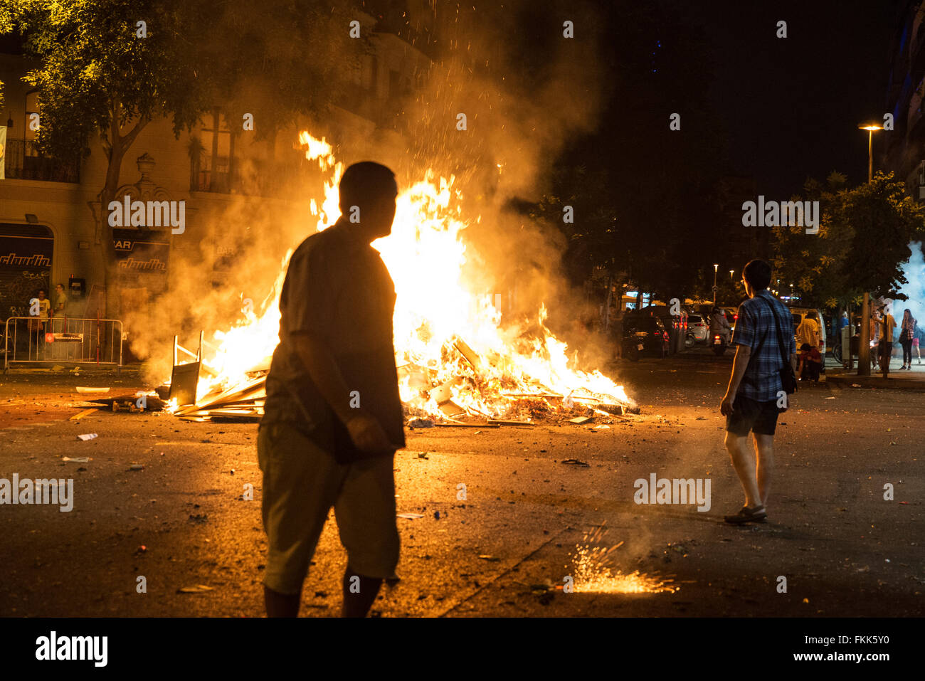 People throwing objects at a bonfire at night to celebrate the ...