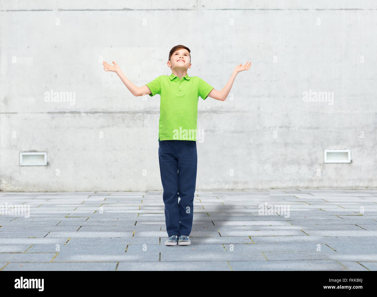 happy boy in polo t-shirt raising hands up Stock Photo - Alamy