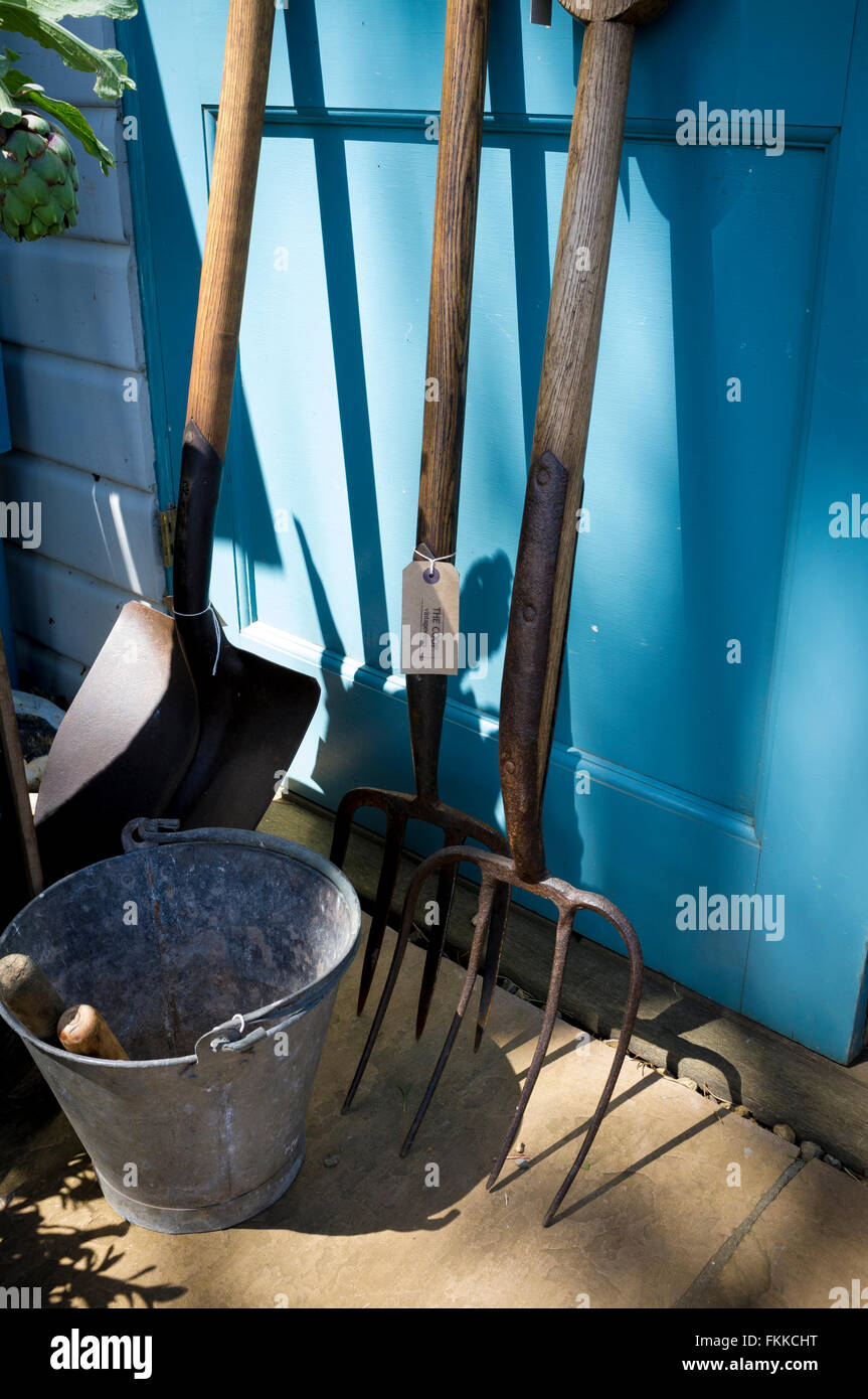 Traditional gardening tools leaning against a blue wall at Wiverton ...