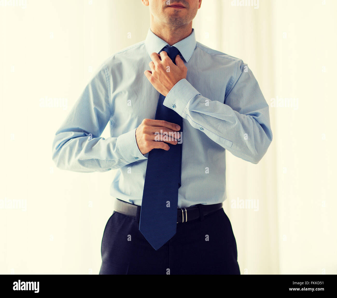close up of man in shirt adjusting tie on neck Stock Photo - Alamy