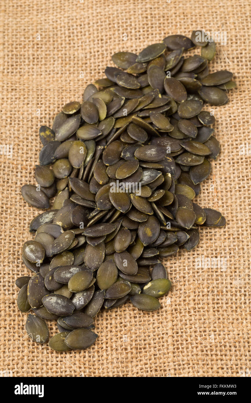 Heap of unshelled pumpkin seeds on burlap background Stock Photo - Alamy