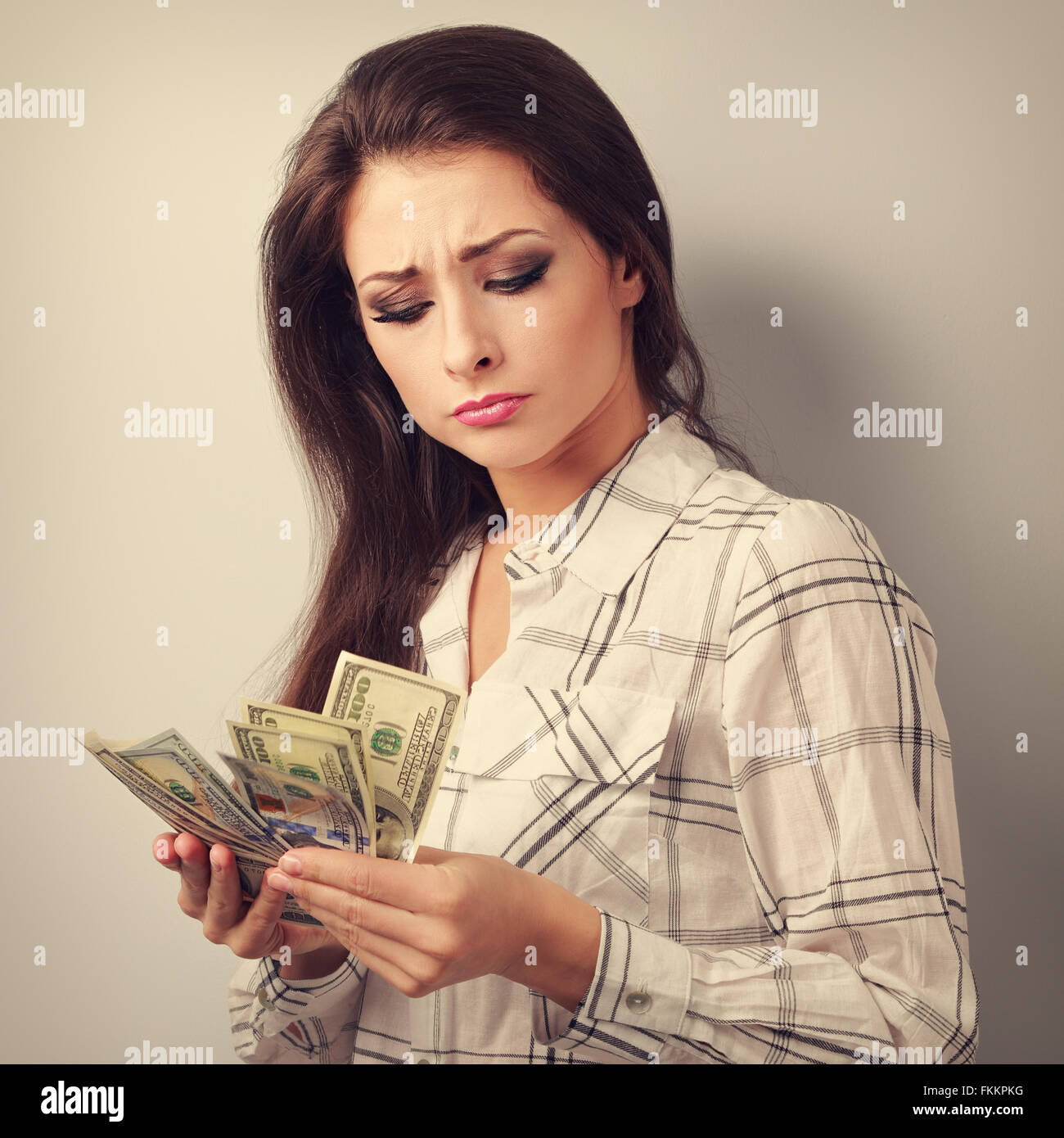 Young unhappy woman looking and counting dollars and thinking how ...