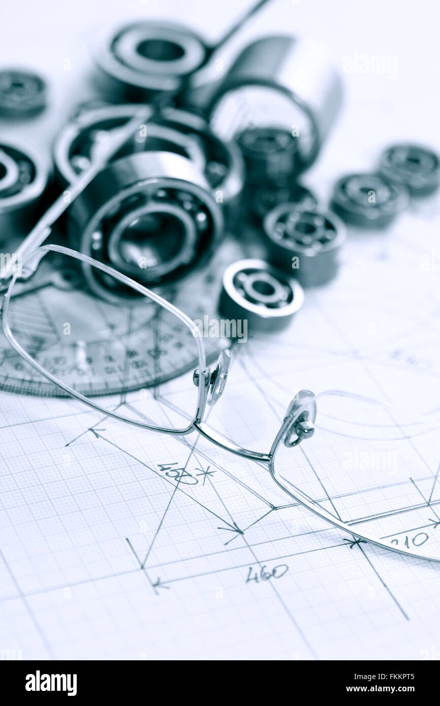 Engineering concept. Few ball bearings near spectacles on graph paper ...