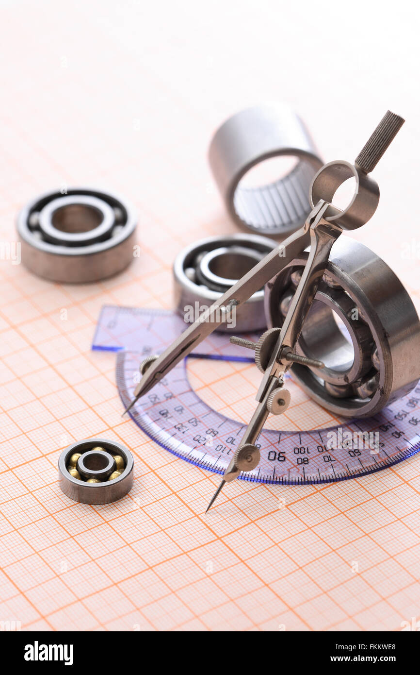 Industrial concept. Divider and ruler near ball bearing on graph paper ...