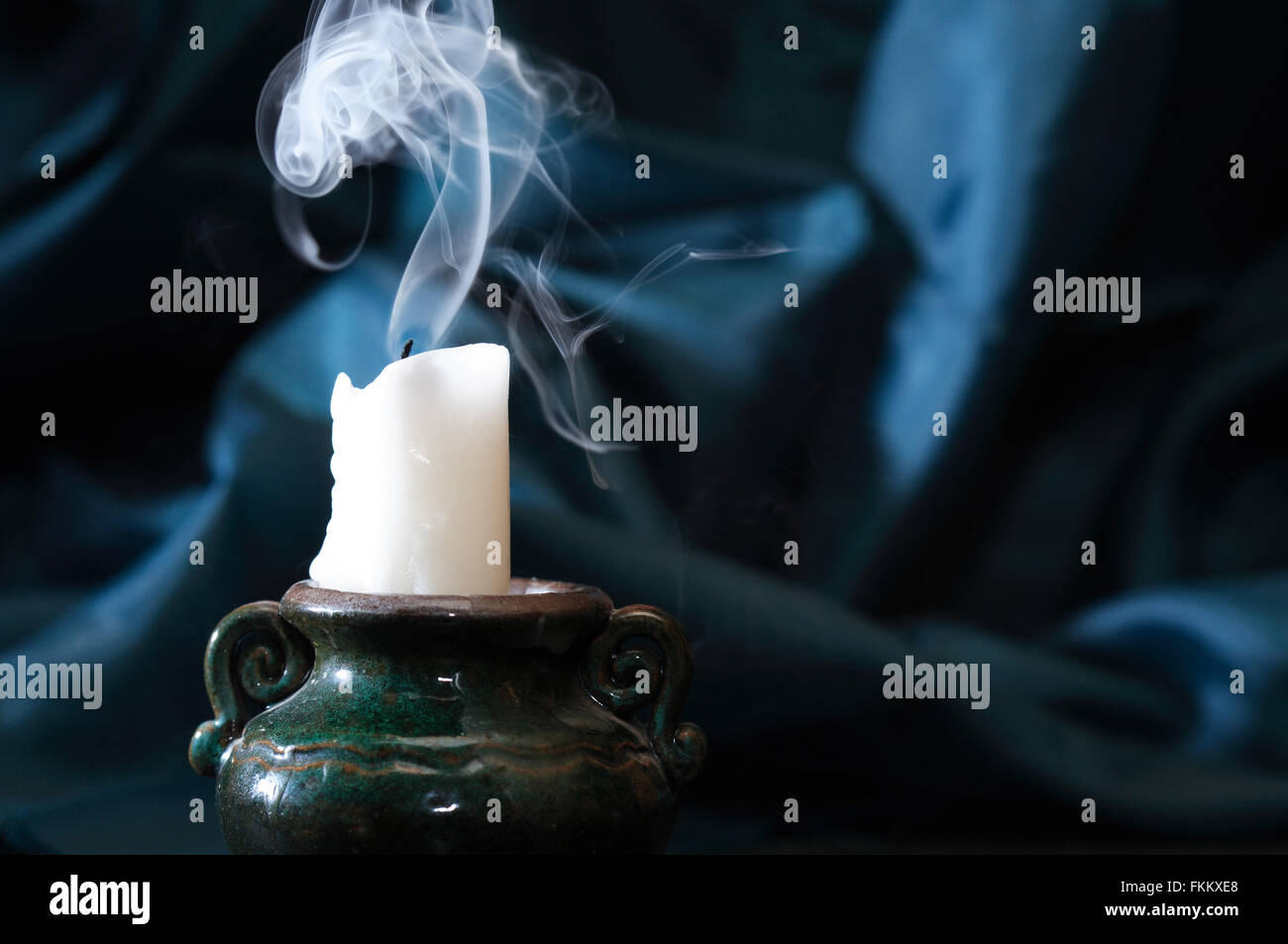 One extinguished candle with smoke on nice fabric background Stock ...