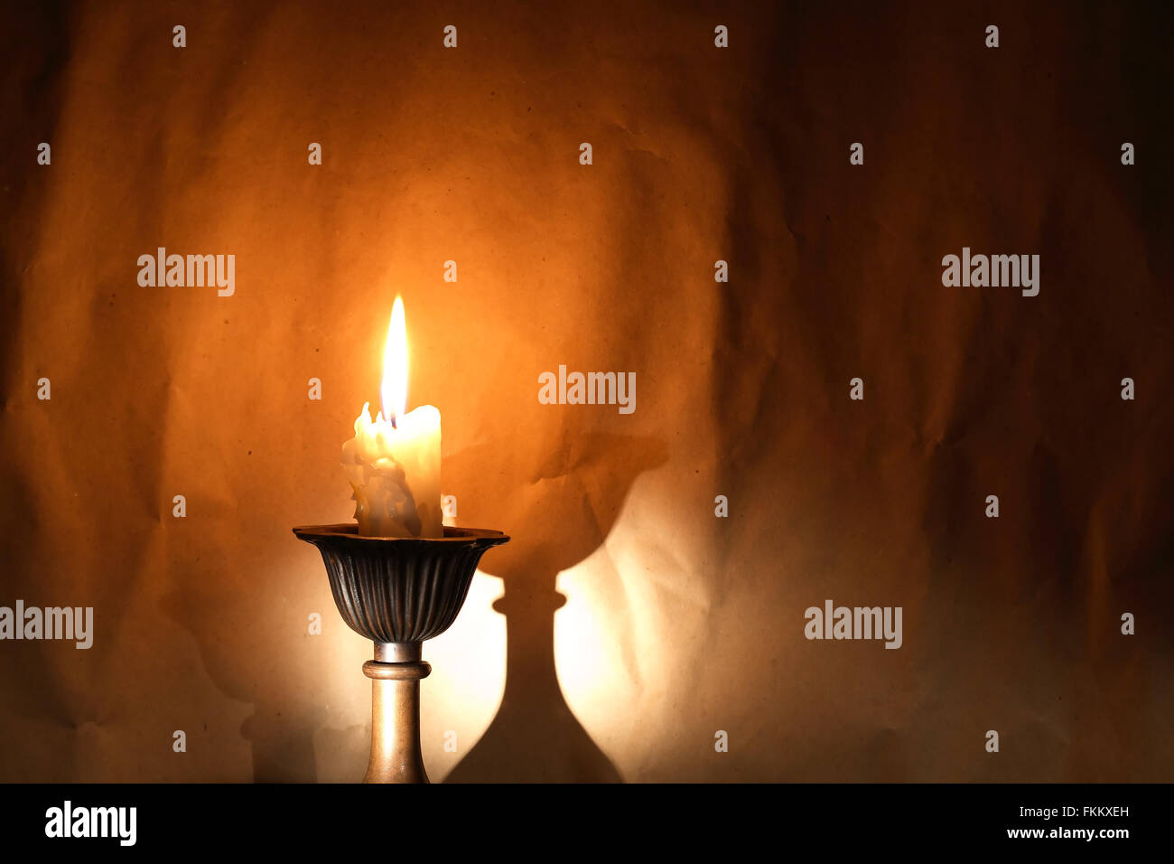 Lighting candle in candlestick on craft paper background Stock Photo ...