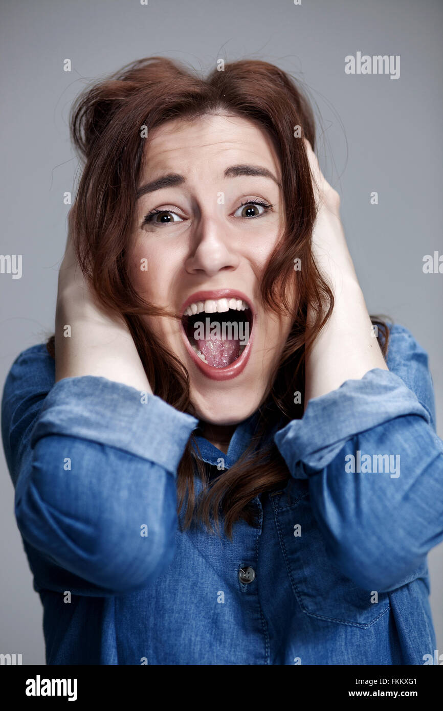 Portrait of young woman with shocked and surprised facial expressions ...