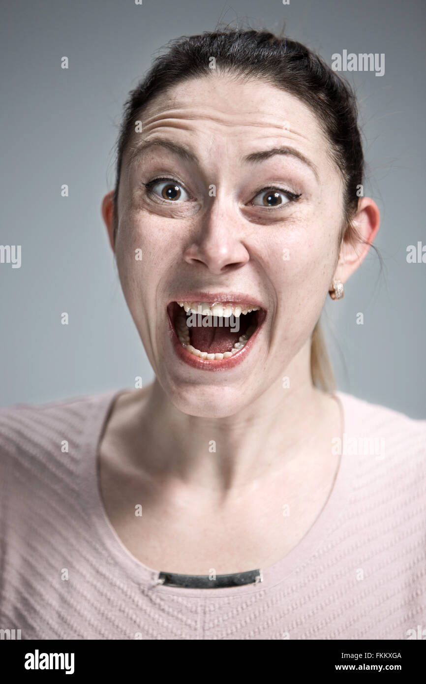 Portrait of young woman with shocked and surprised facial expressions ...