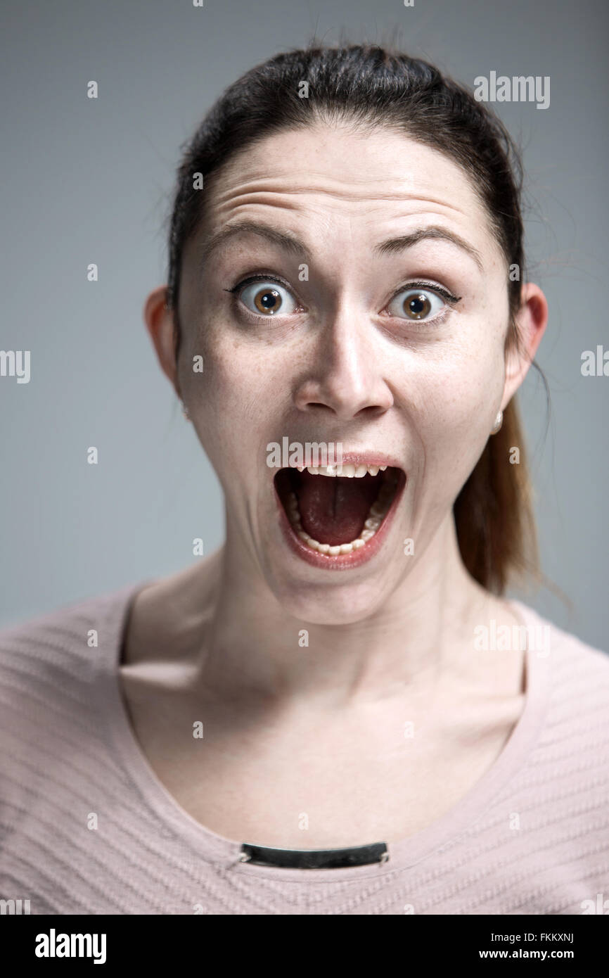 Portrait of young woman with shocked and surprised facial expressions ...
