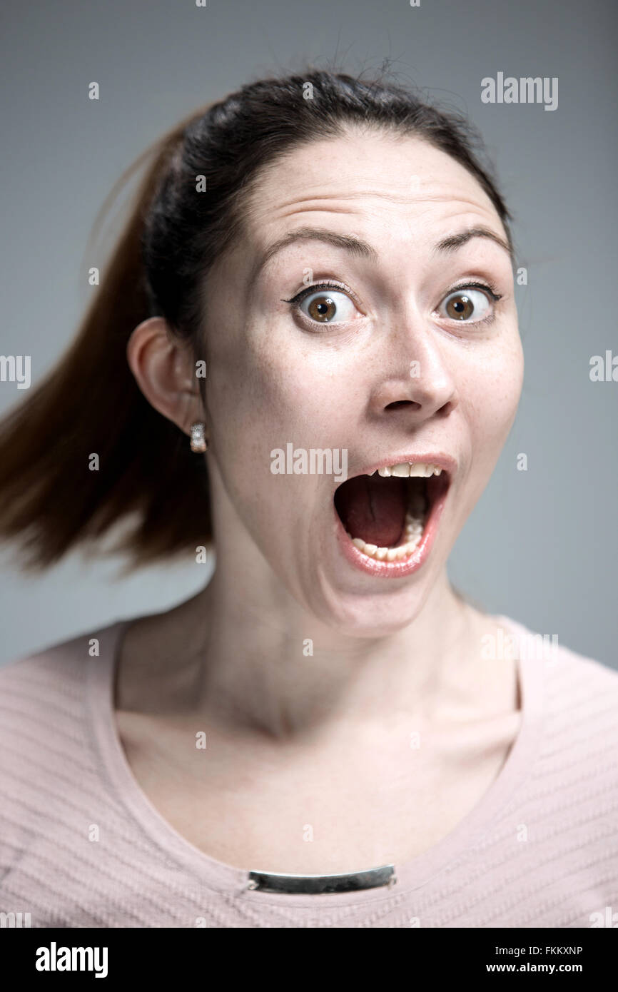 Portrait of young woman with shocked and surprised facial expressions ...