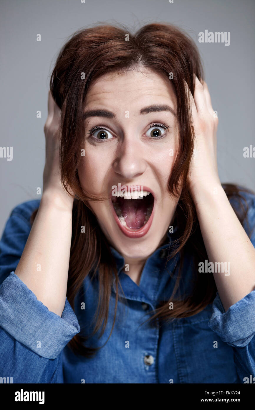Portrait of young woman with shocked and surprised facial expressions ...