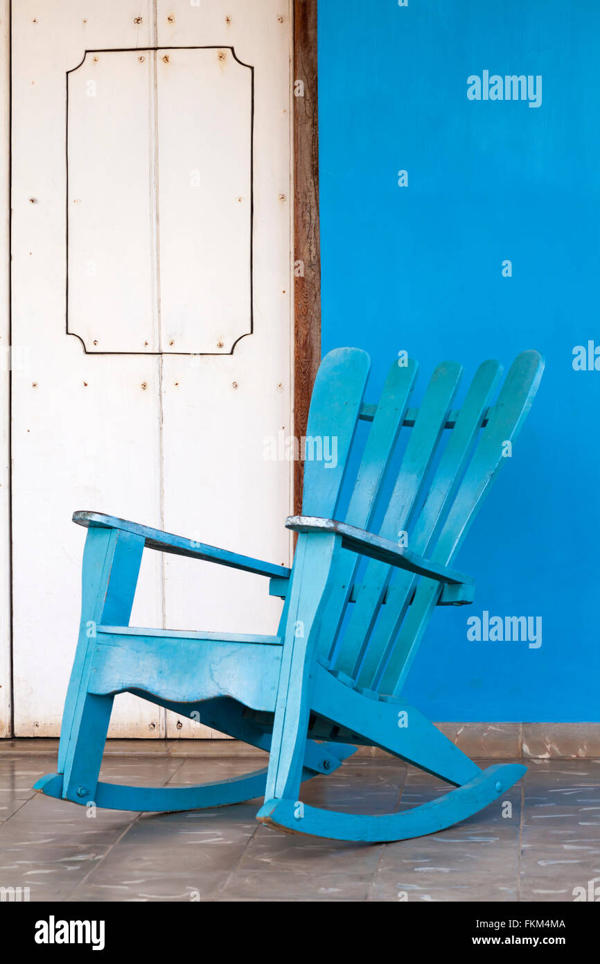 Traditional Blue rocking chair against blue wall and white wooden door ...