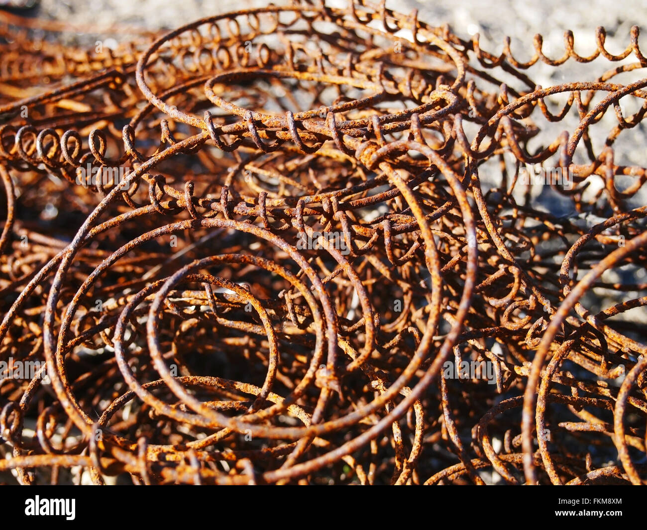 A pile of rusty, discarded, old couch springs on the ground in an empty ...