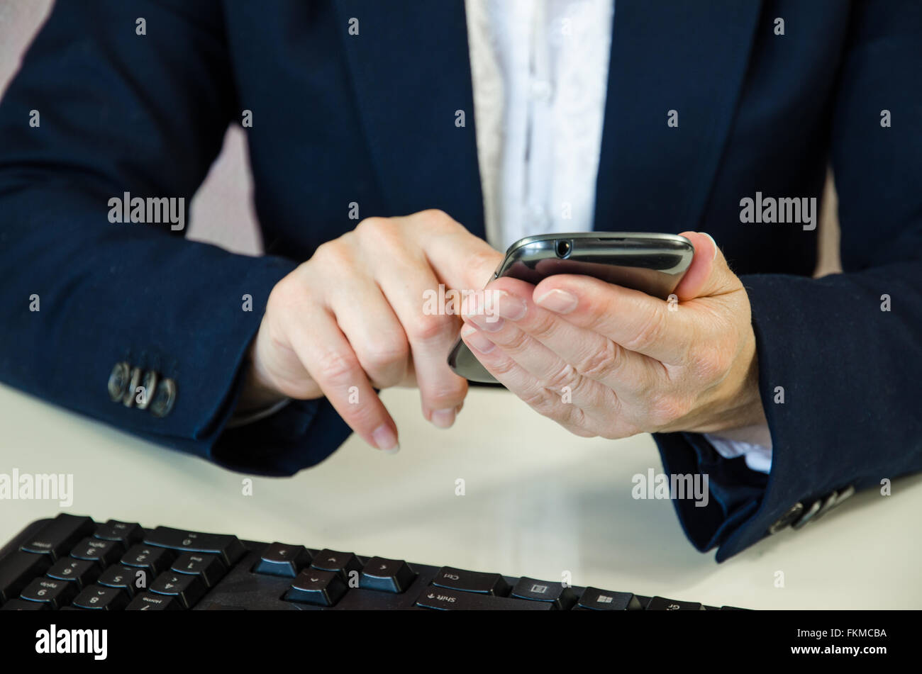 female hand typing into mobile phone behing working desk Stock Photo ...