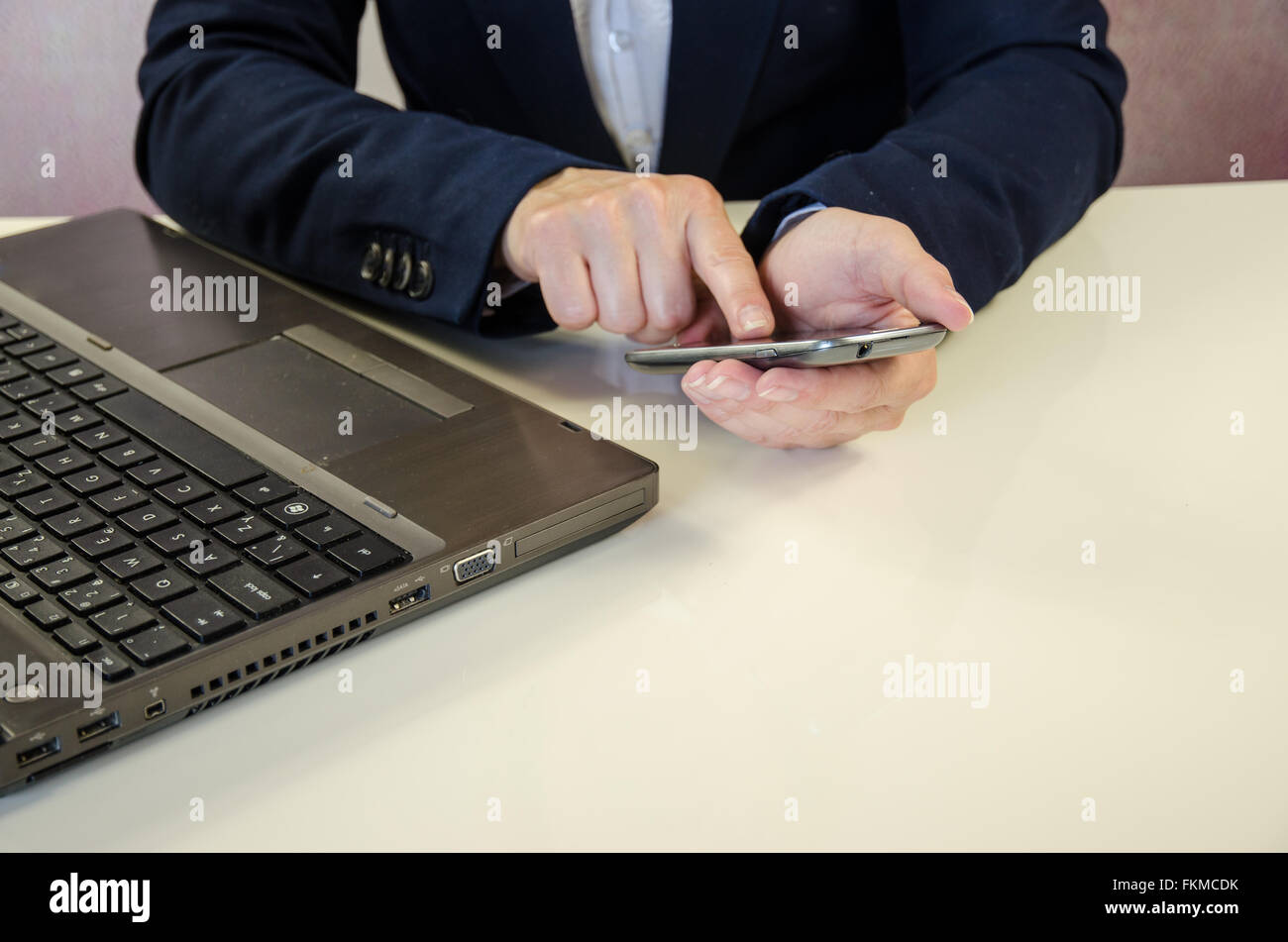 female hand typing into mobile phone behing working desk Stock Photo ...