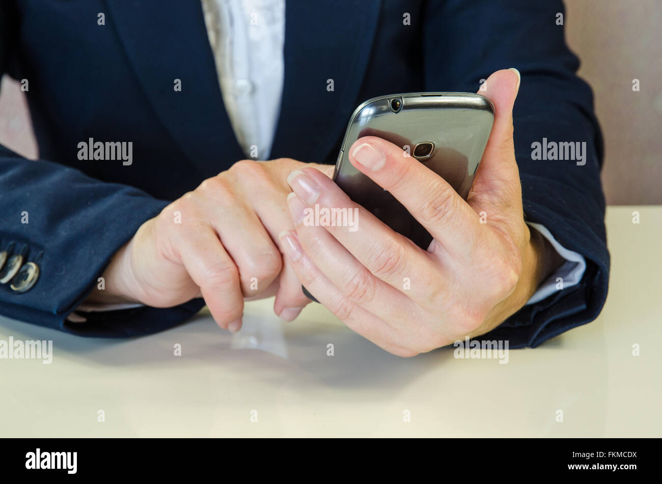 female hand typing into mobile phone behing working desk Stock Photo ...