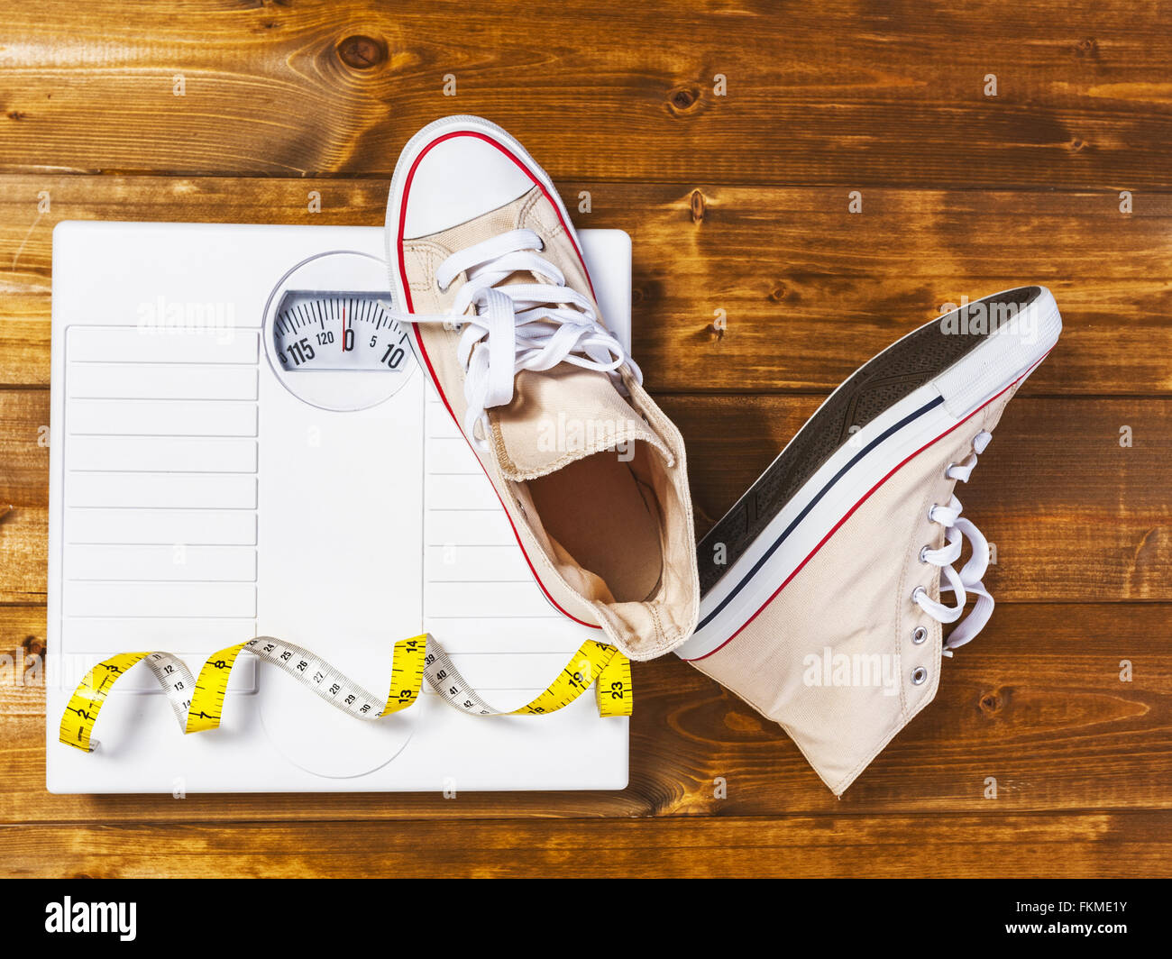 Weight scale with sport shoes and measuring tape on wooden background ...