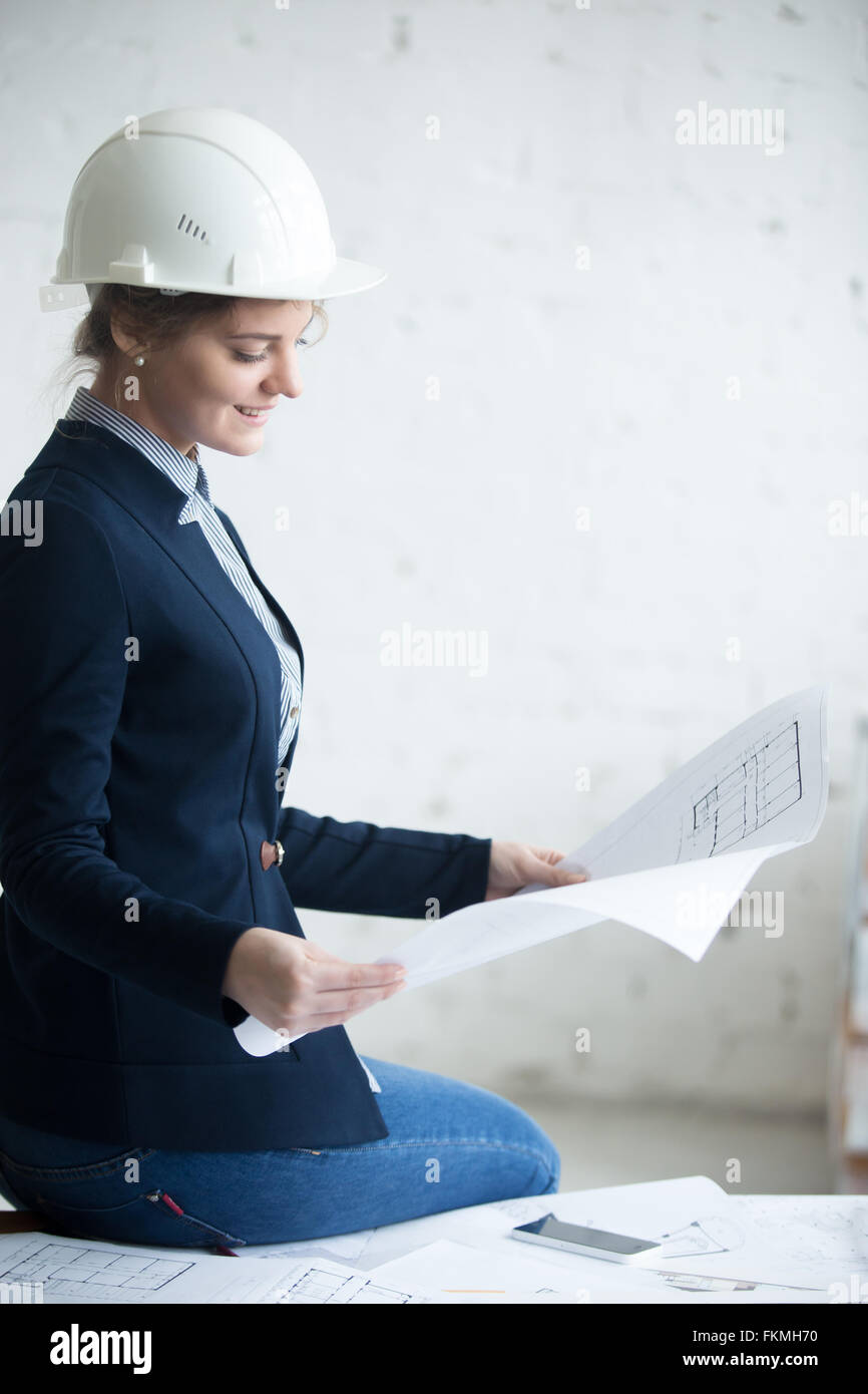 Portrait of beautiful happy smiling young engineer woman in white hard ...