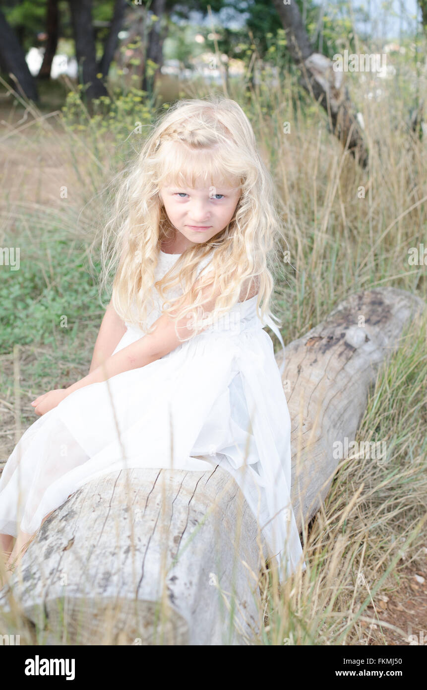 adorable innocent child with long hair in white dress in forrest Stock ...