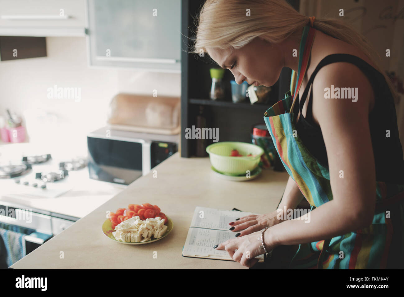 Young woman looking up in a recipes book Stock Photo - Alamy