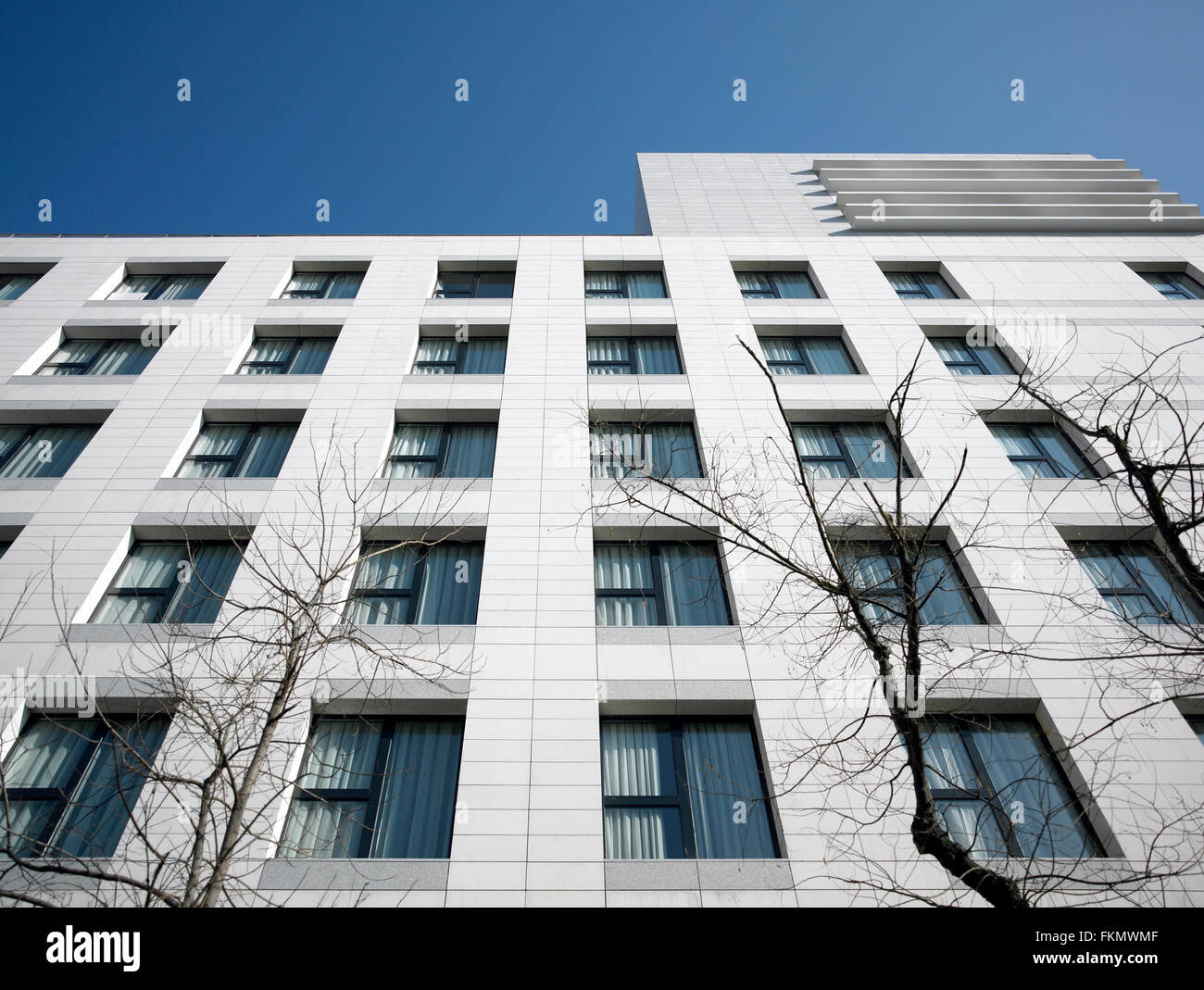 Modern building facade with metallic coating and trees. Horizontal ...